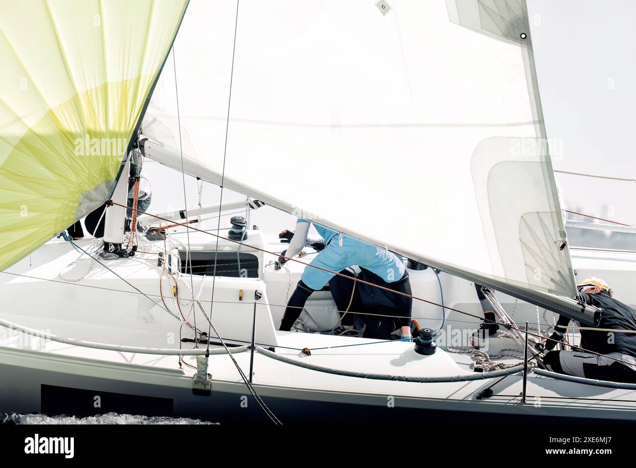 Sailboat crew members are diligently adjusting sails during a regatta ...