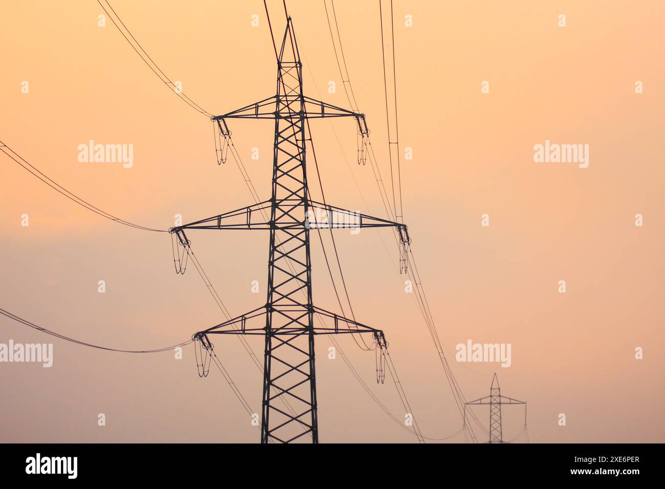 Setting sun behind silhouettes of electricity pylons and power lines ...