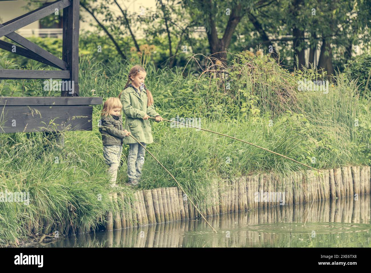 two little fisher girls with rods on a river bank Stock Photo - Alamy