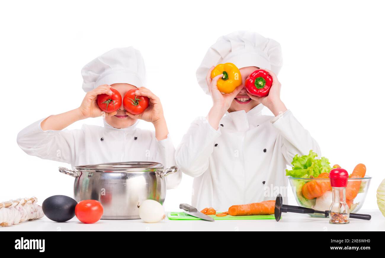 two little cooks in uniform playing vegetables for soup in the kitchen ...