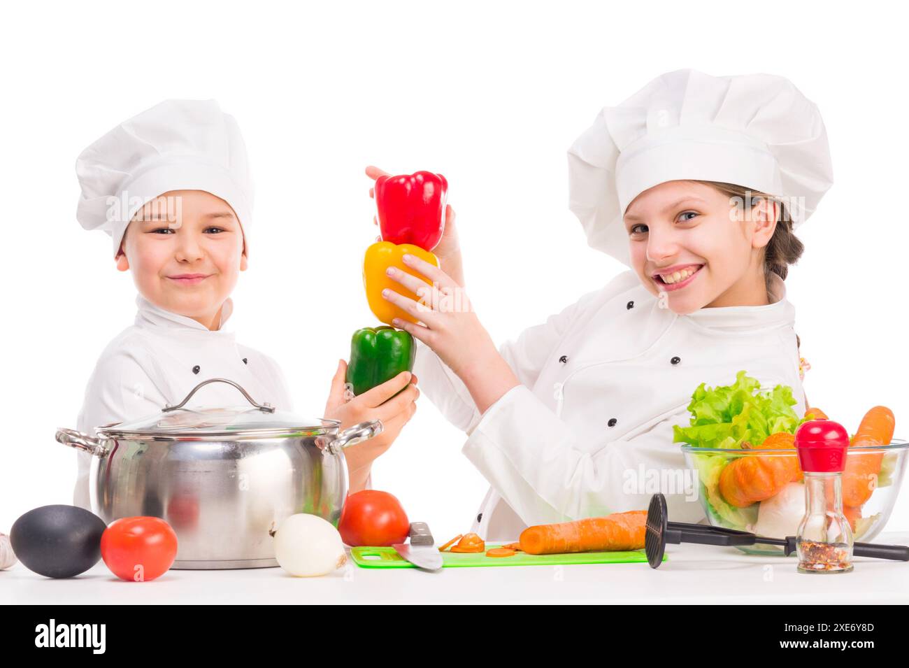 two little cooks in uniform playing vegetables for soup in the kitchen ...
