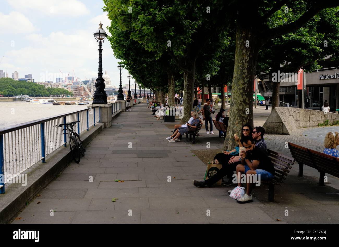 People sitting on benches watching the River Thames, Southbank, London ...