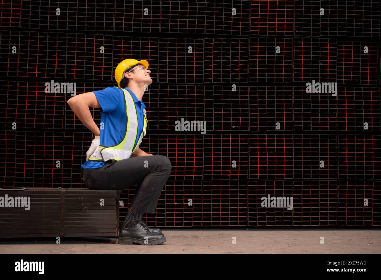 Portrait of a male worker wearing a safety vest and helmet sitting on a ...