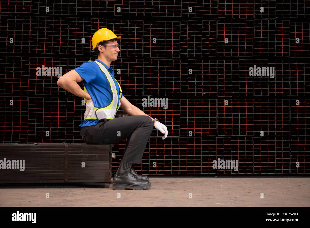 Portrait of a male worker wearing a safety vest and helmet sitting on a ...