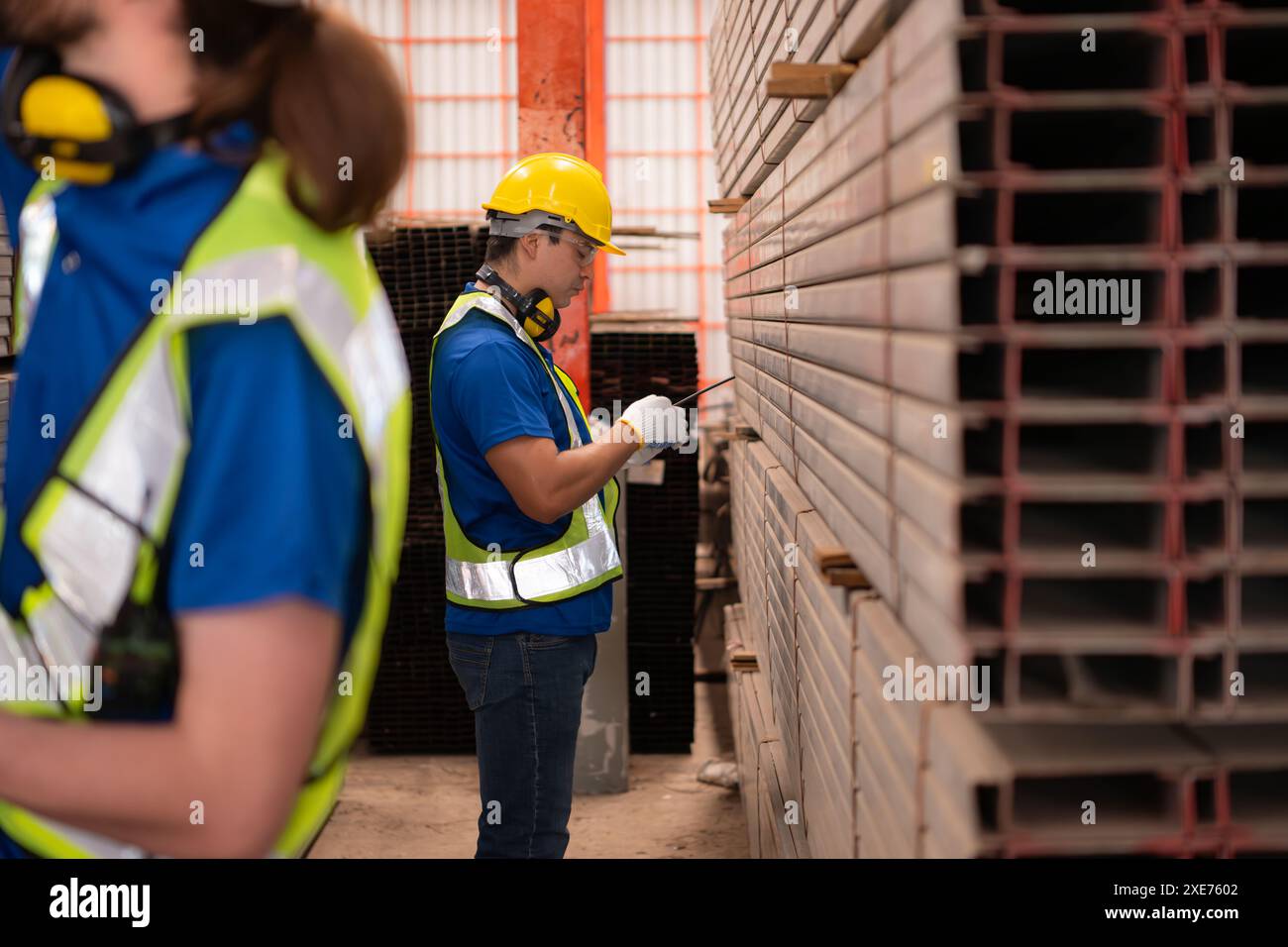 Warehouse workers in hard hats and helmets stand in the warehouse to ...