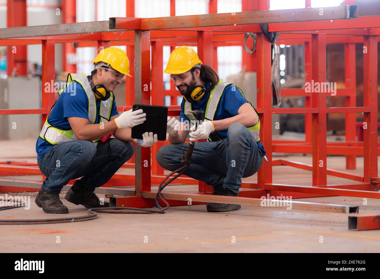 Portrait of two workers using digital tablet sit in front of the red ...