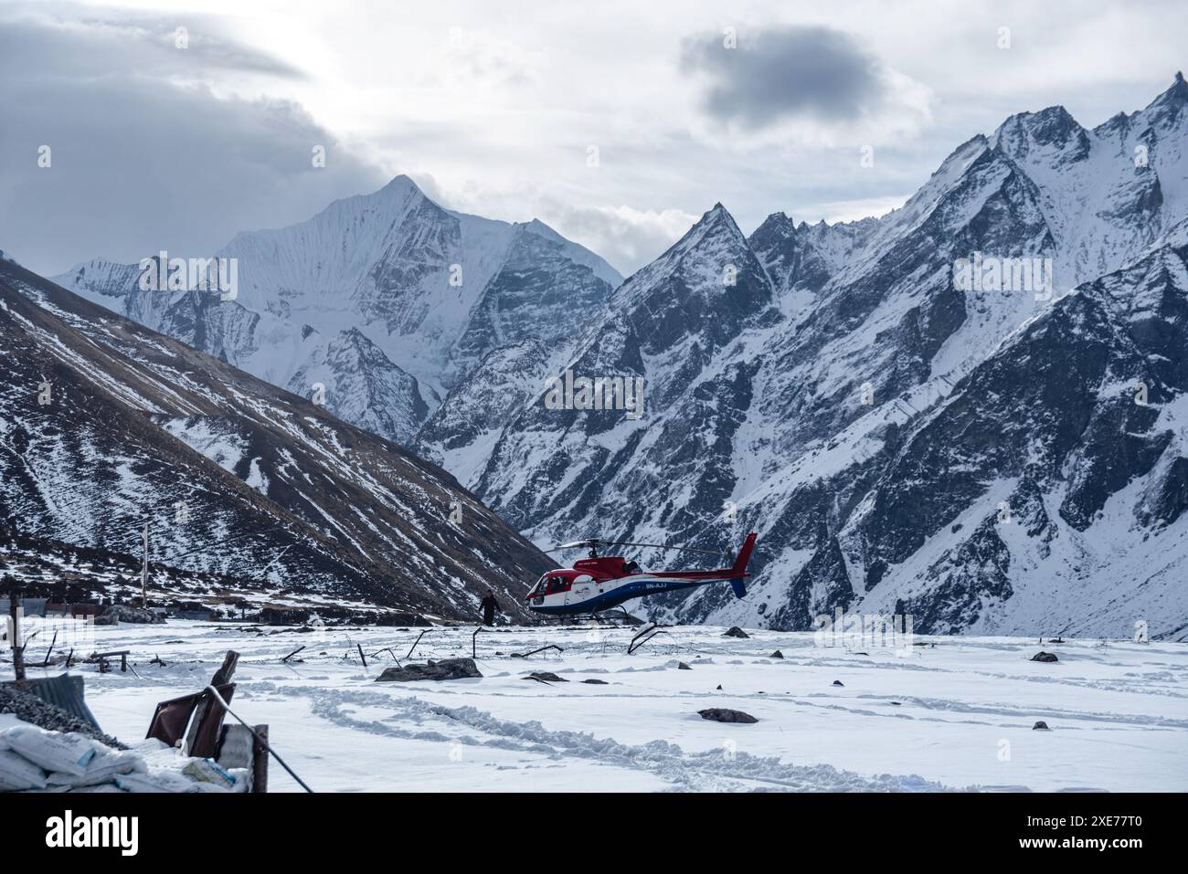 Helicopter landing on a snowy field in front of high altitude mountain ...