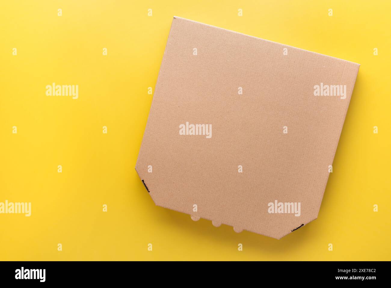 Pizza closed carton box on uniform yellow background flat lay mockup ...