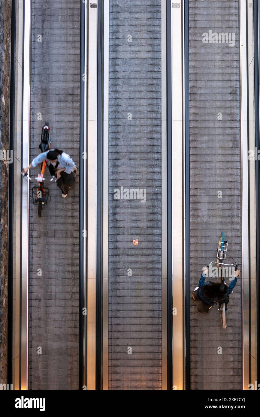 Two women pushing their bicycles on a travelator leaving the ...