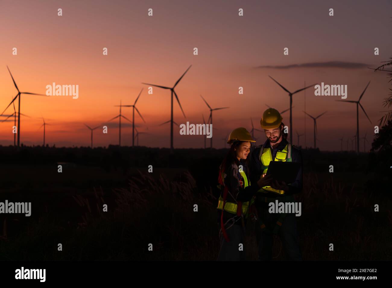 Engineers working on wind turbines farm at sunset, Wind turbines are ...