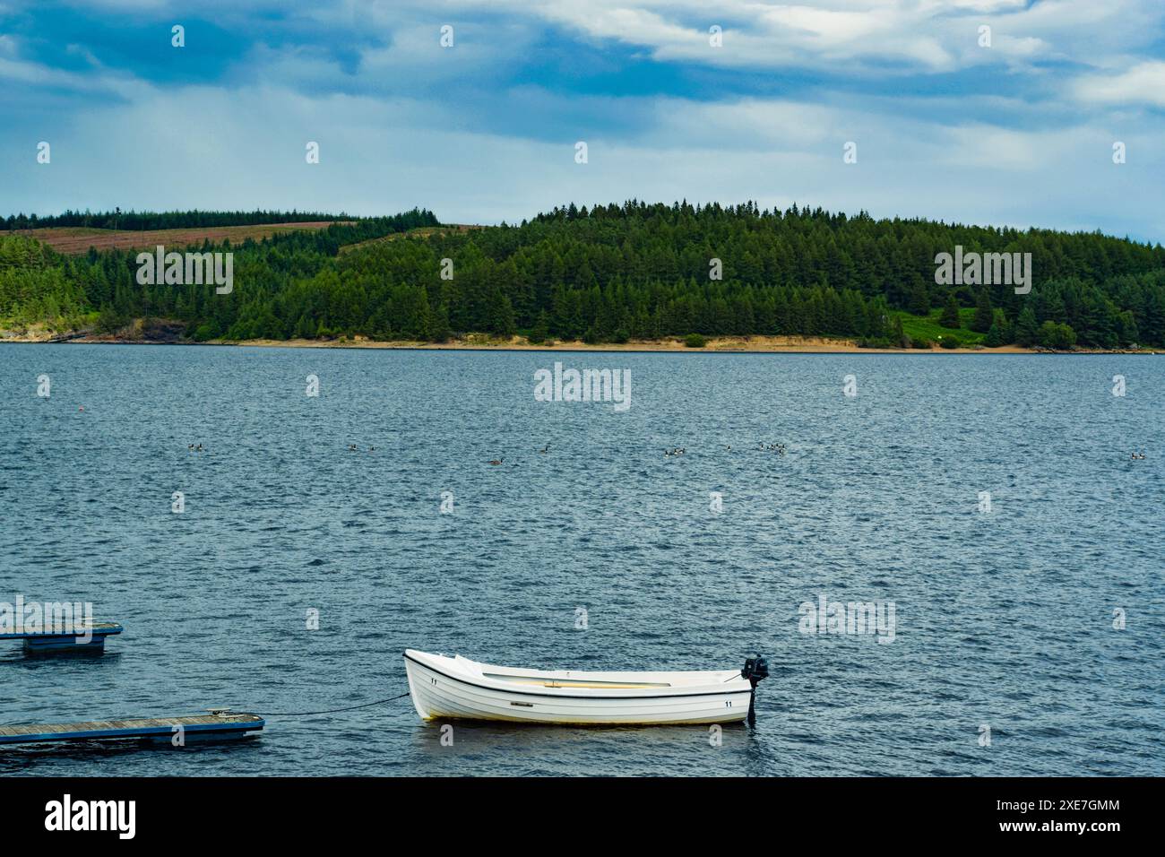 Lonely, single boat drifting along a lake / reservoir. Hills in the ...