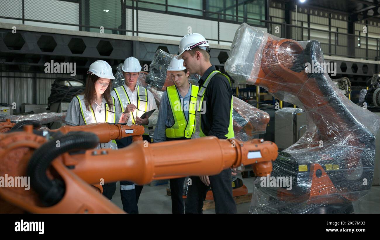 Group of engineers and technicians working together in a robotic arm factory. Inspecting robot ...