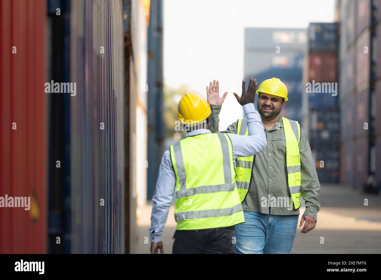 Both of workers in a container storage yard greeting each other during ...