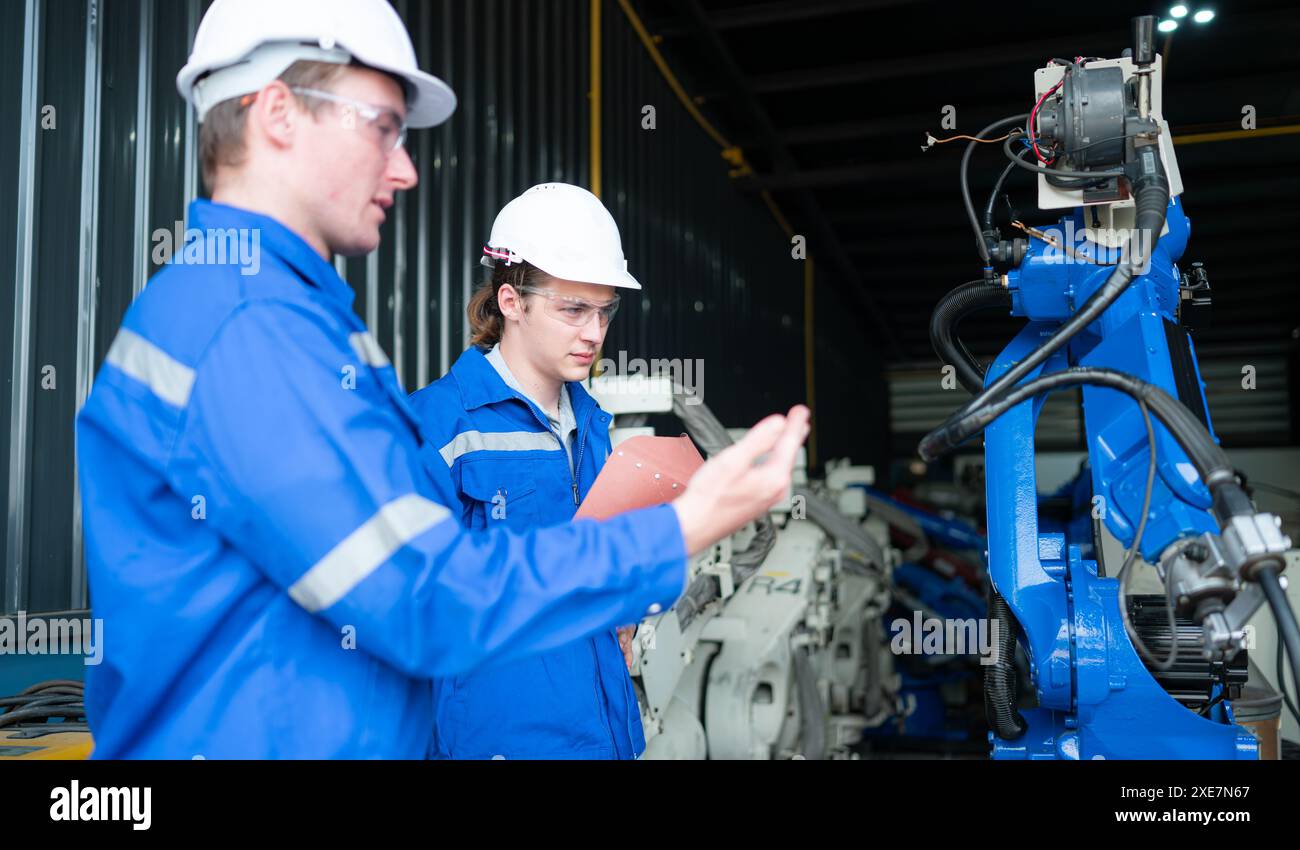 Industrial workers working with robotic arm welding machine in factory ...