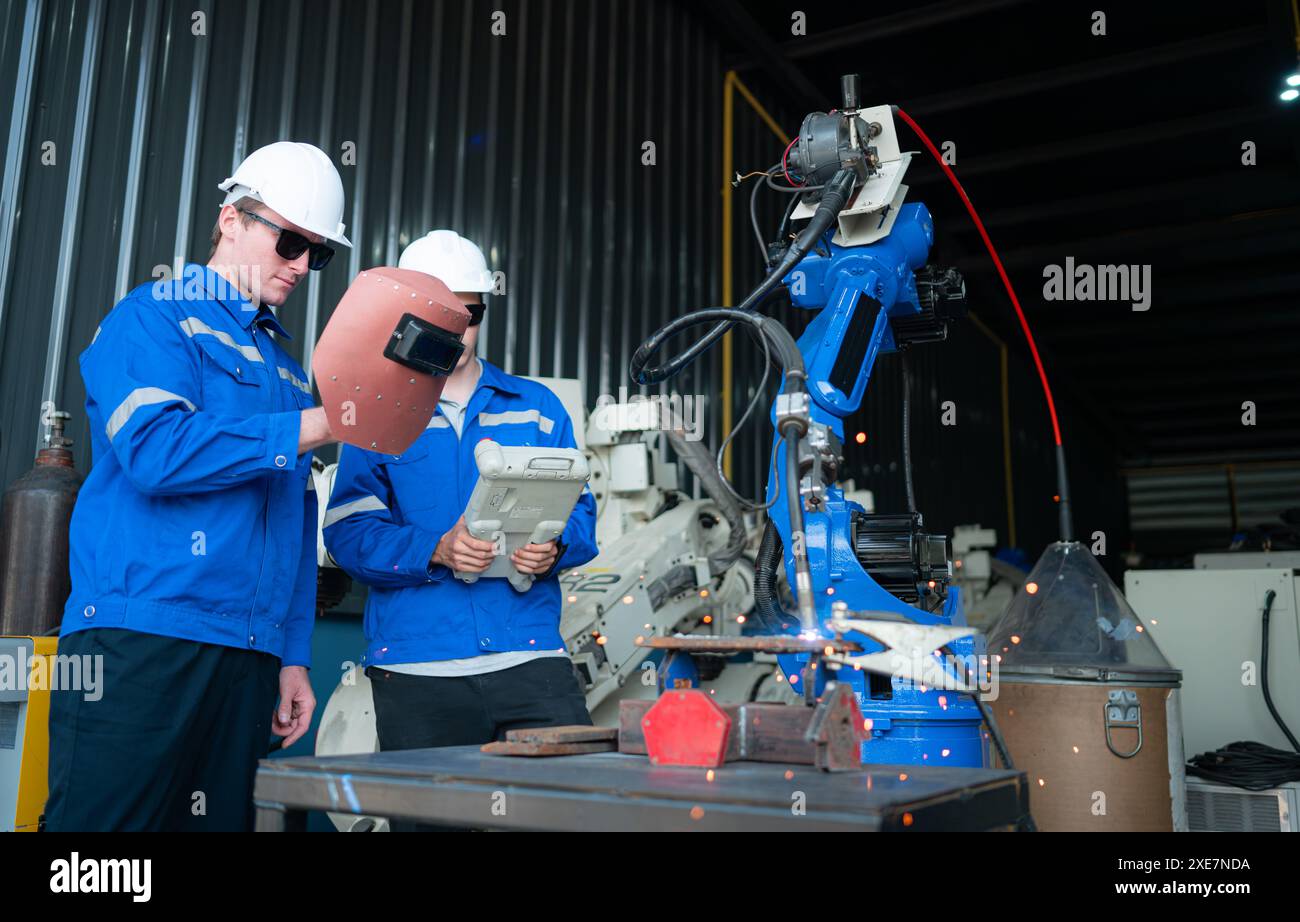 Industrial workers working with robotic arm welding machine in factory ...