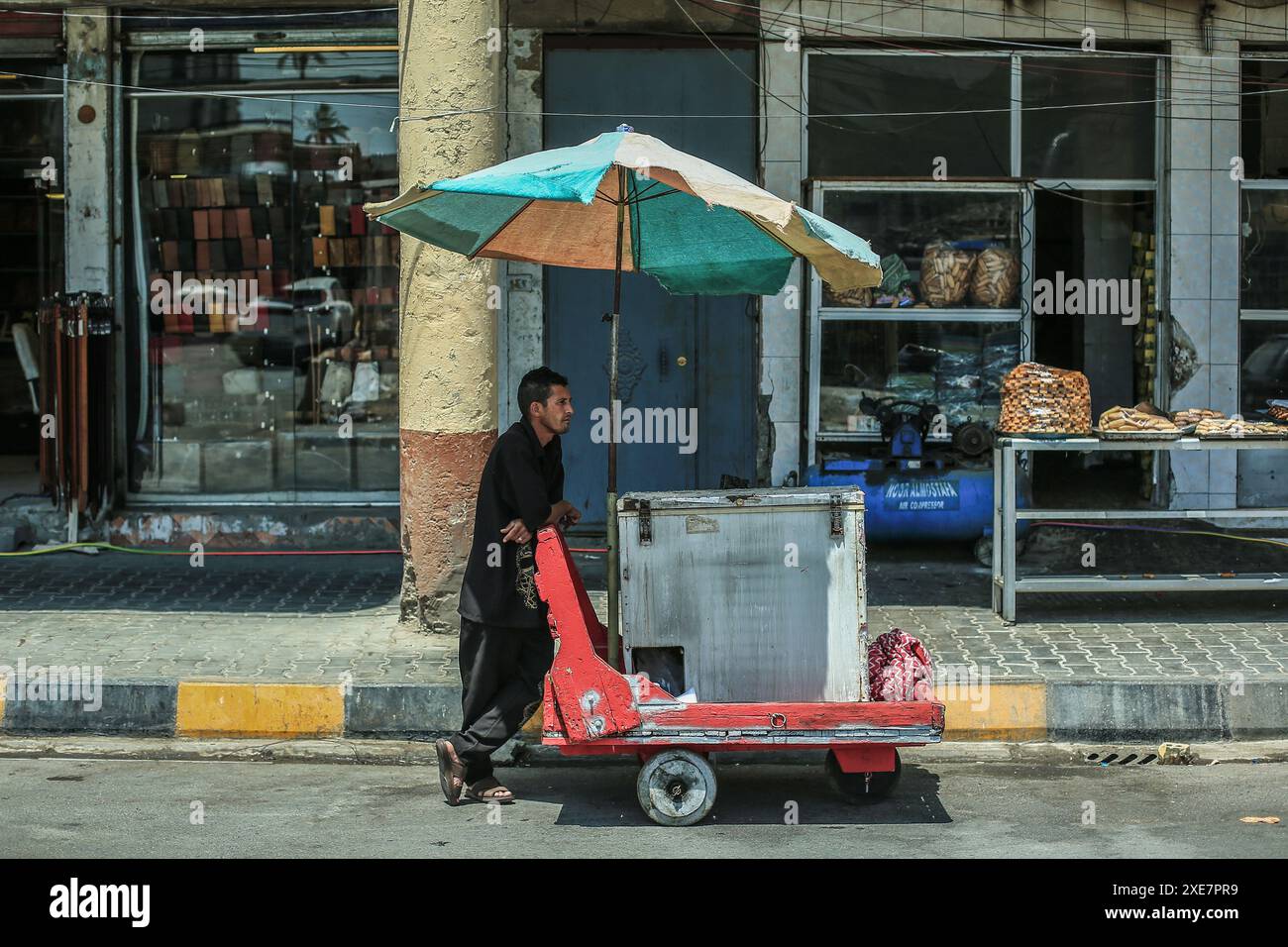 26 June 2024, Iraq, Baghdad: An Iraqi vendor shelters from the sun ...