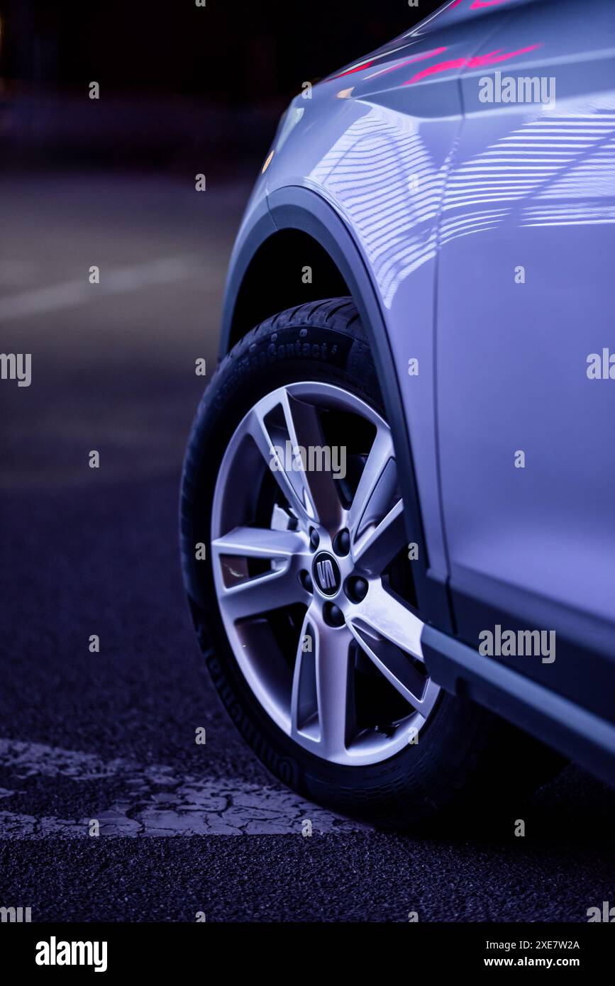 silver SEAT Ateca reflecting violet light at night. Front wheel and ...