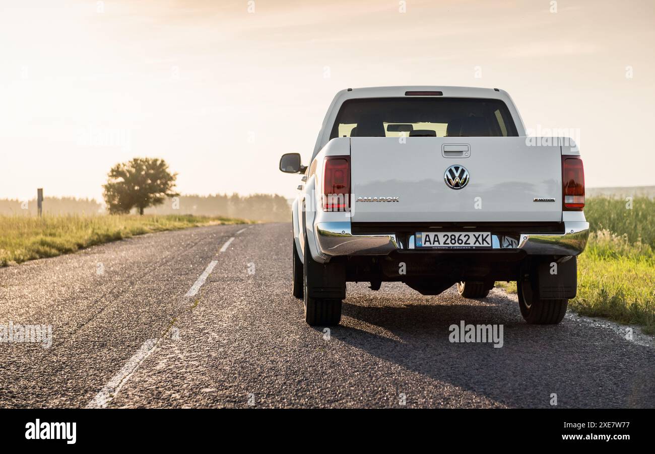 white Volkswagen Amarok on a countryside paved road in late afternoon ...