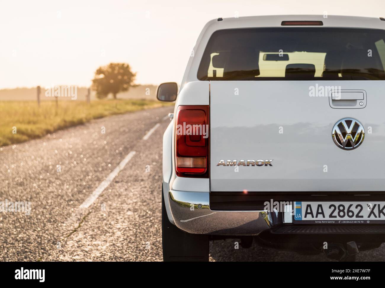 white Volkswagen Amarok on a countryside paved road in late afternoon ...