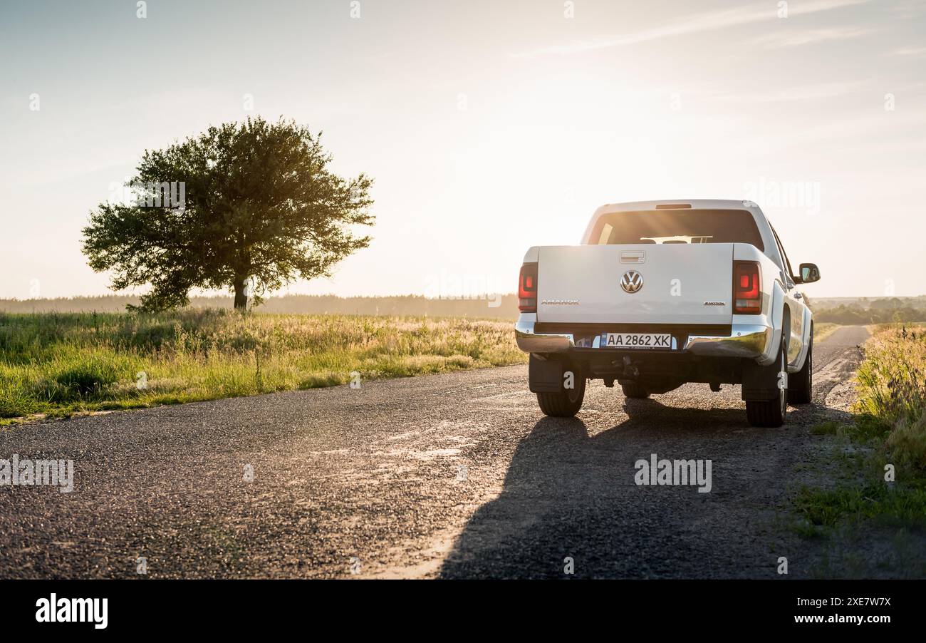 white Volkswagen Amarok on a countryside road in late afternoon. Rear ...