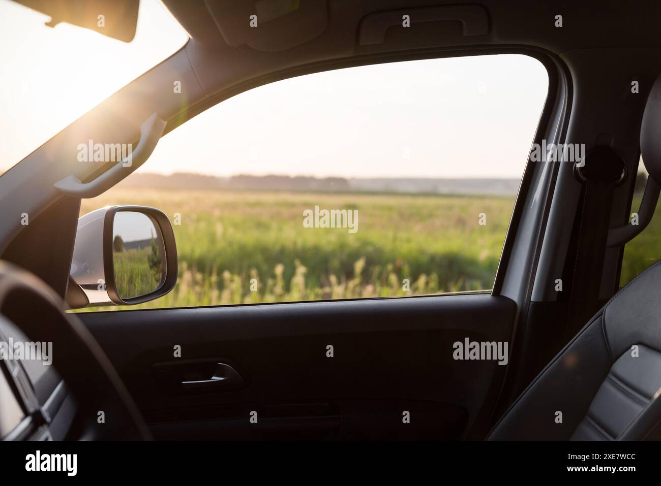 Car side window. Looking at the green meadow in the background through ...