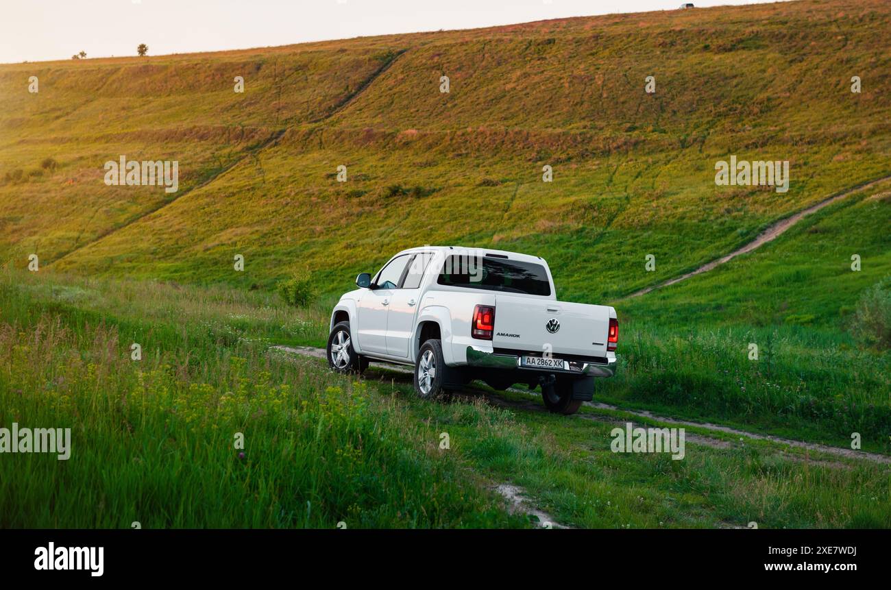 white Volkswagen Amarok near green hill. Rear three quarter view of ...