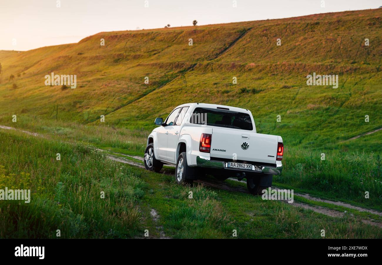 white Volkswagen Amarok near green hill. Rear view of double cab VW ...