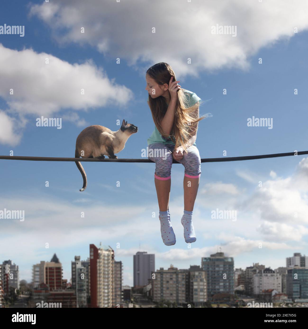 A little girl sitting on a rope with cat above a cityscape . Concept of ...