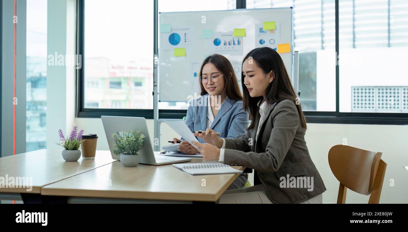 Two Businesswomen Collaborating in Modern Office with Laptops and Documents, Analyzing Data on ...