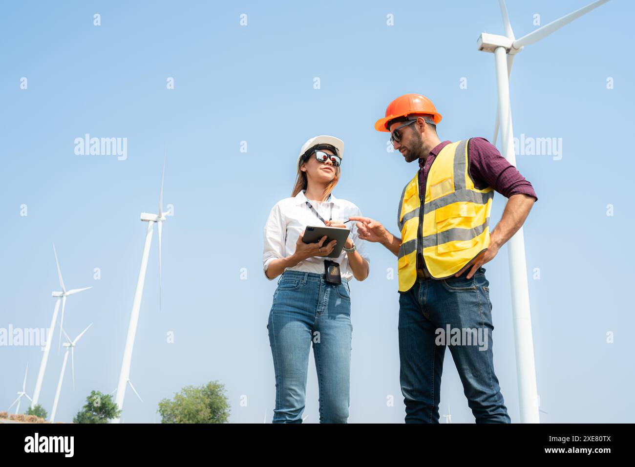 Engineer and architect discussing on wind turbine farm with blue sky ...