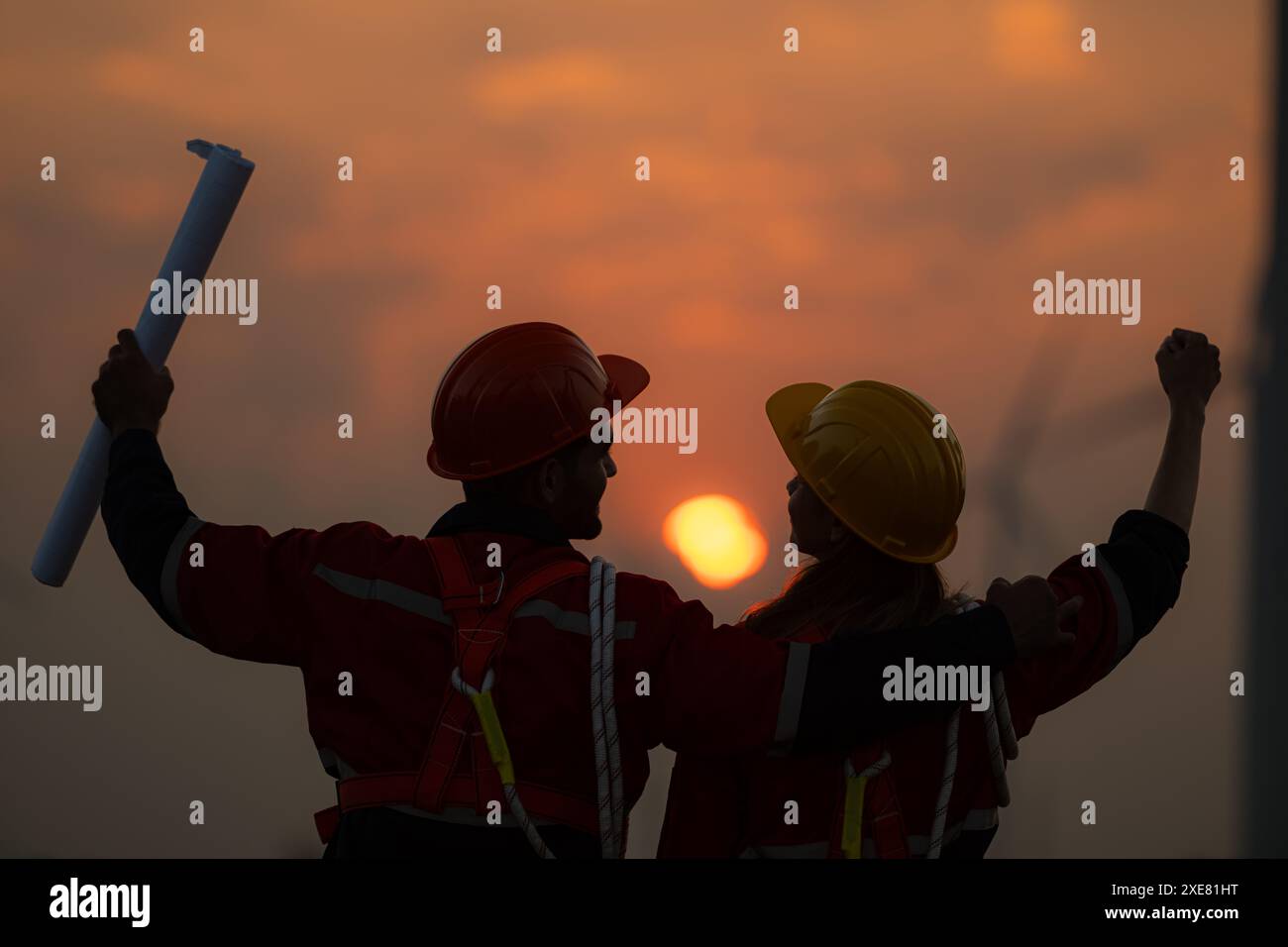 Silhouette of engineer and technician with a wind farm and sunset ...