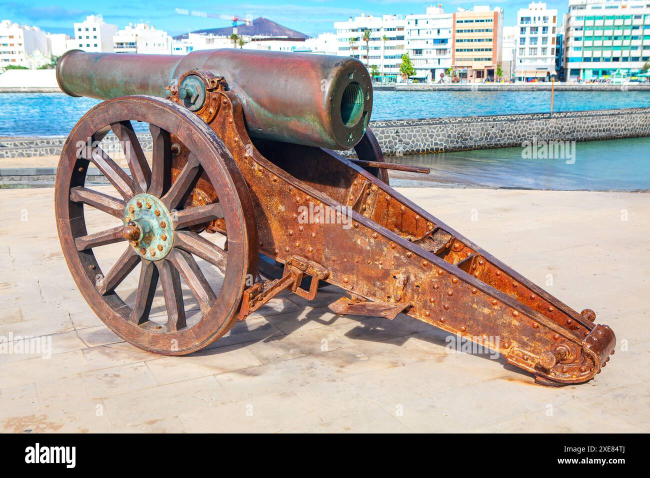Rusted cannon on a concrete surface. Surrounded by a cityscape with ...