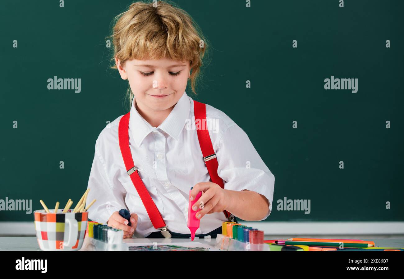 Portrait school kid boy doing art homework, holding pencil, writing ...