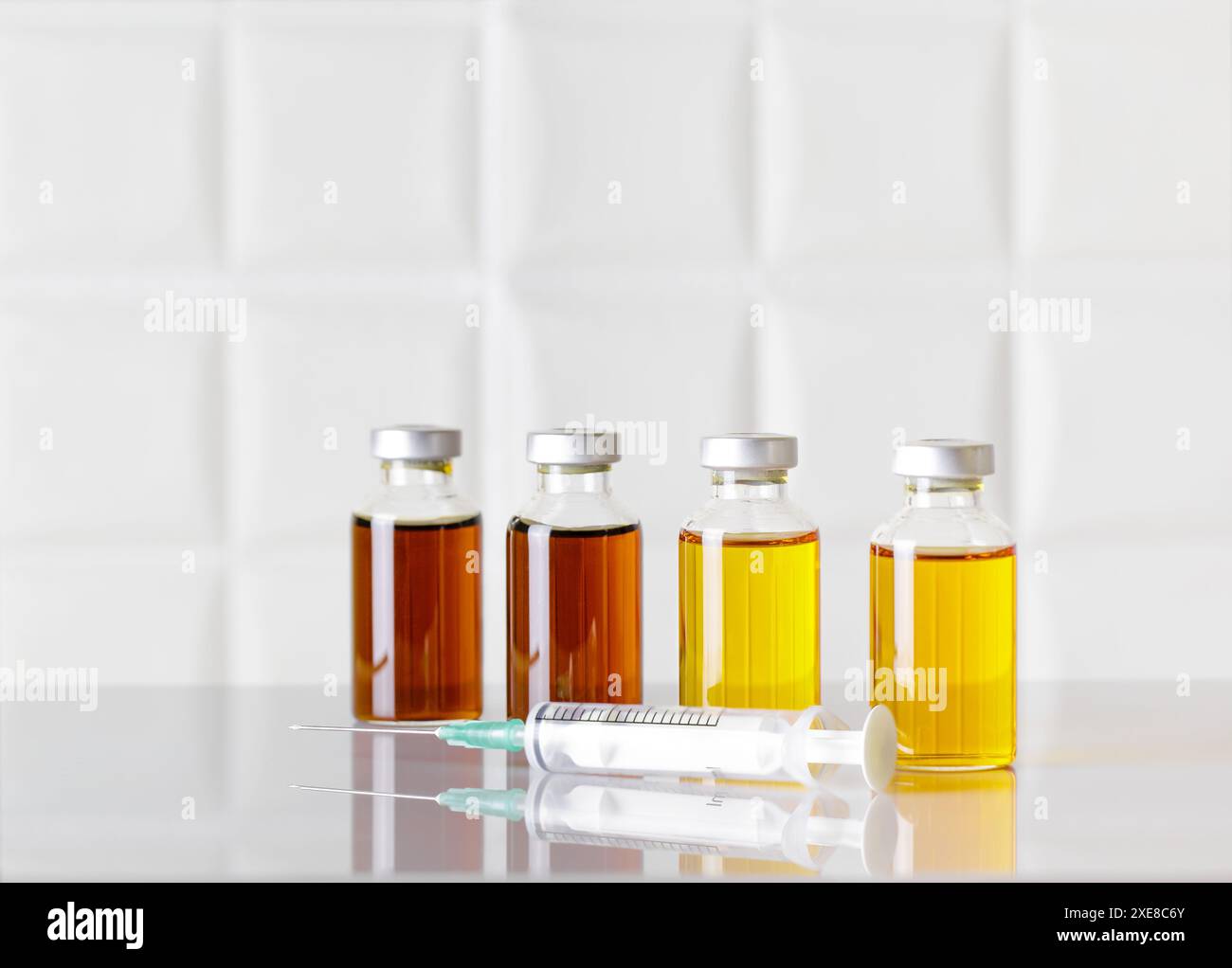 Group of glass bottles of injectable medicine and a syringe on white ...