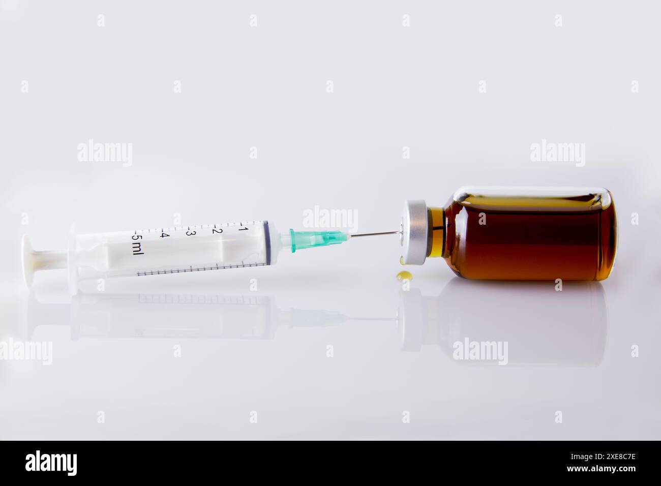 Medical syringe with needle stuck in a bottle of injectable medicine ...