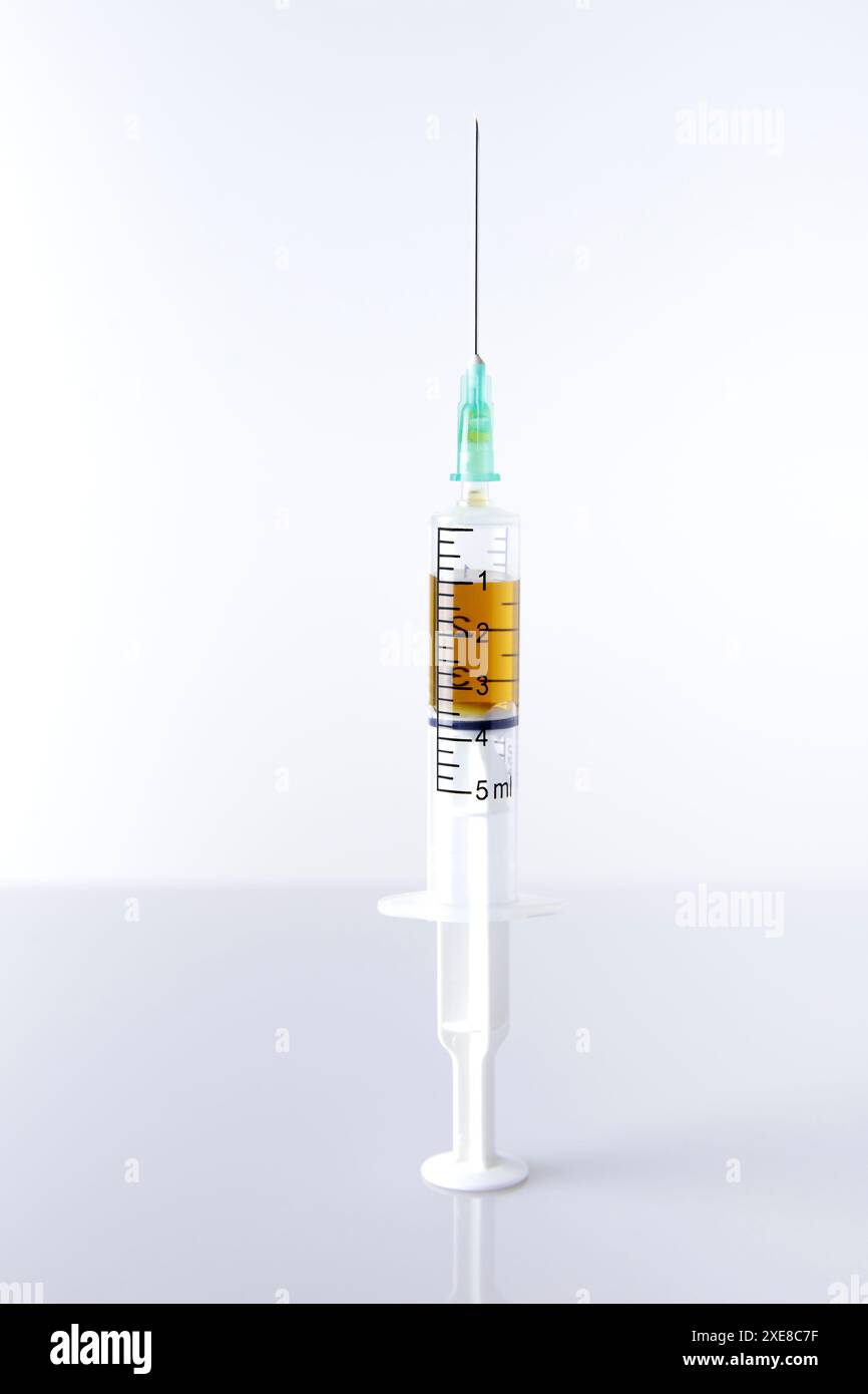 A syringe with medicine inside. Close up. A syringe, upright on a white ...