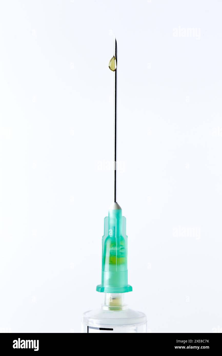 Close-up of the needle of a syringe, with a drop on the needle ...