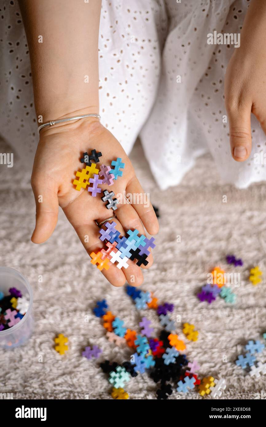 a multi-colored small puzzle set in a womans hands Stock Photo - Alamy