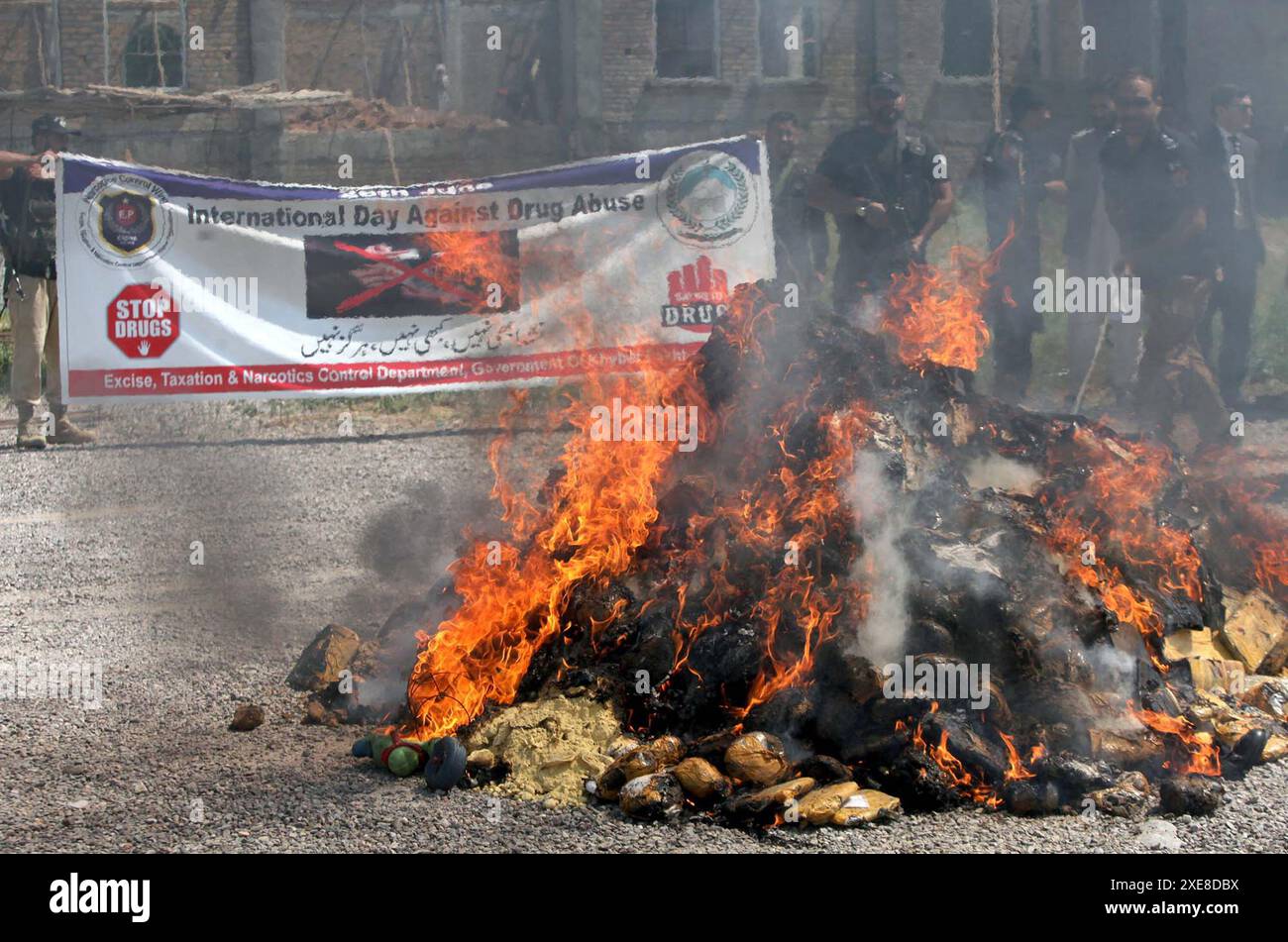Anti-Narcotics Force (ANF) officials stand alert near burning pile of ...