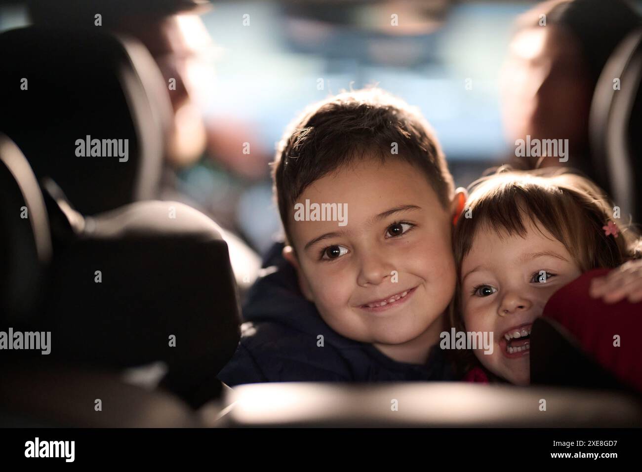 A young brother and sister enjoying a car ride together, immersed in ...