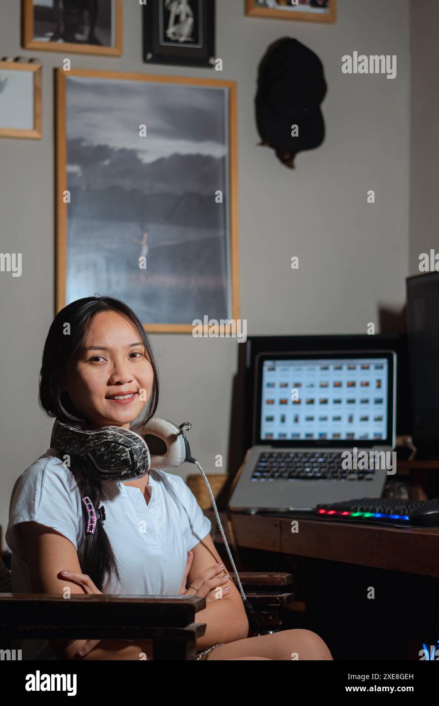 A woman sitting in a home office with a laptop and computer monitor ...