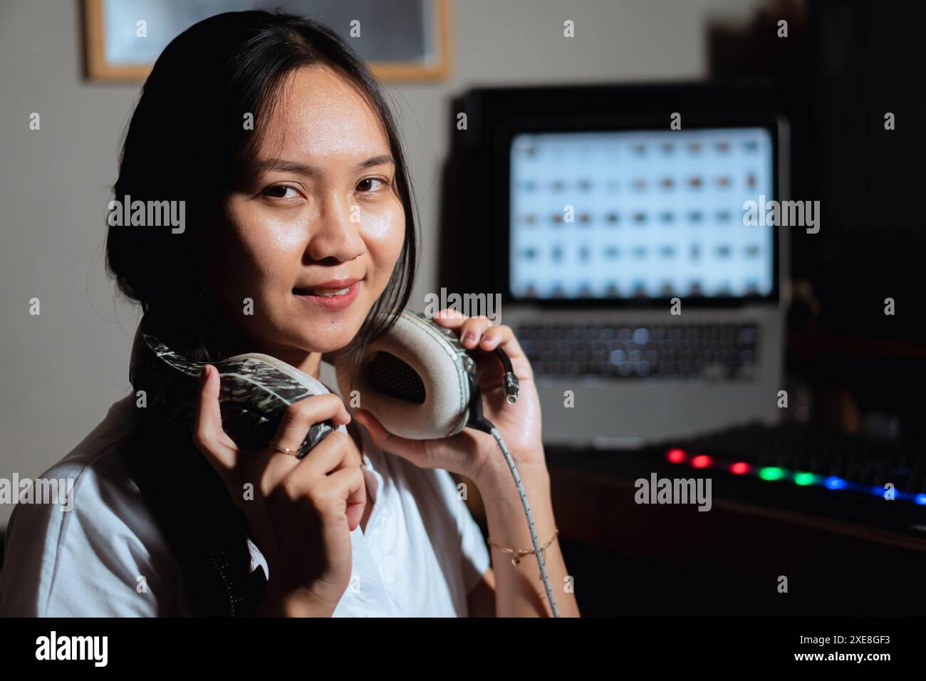 A woman holding headphones around her neck, sitting in front of a ...