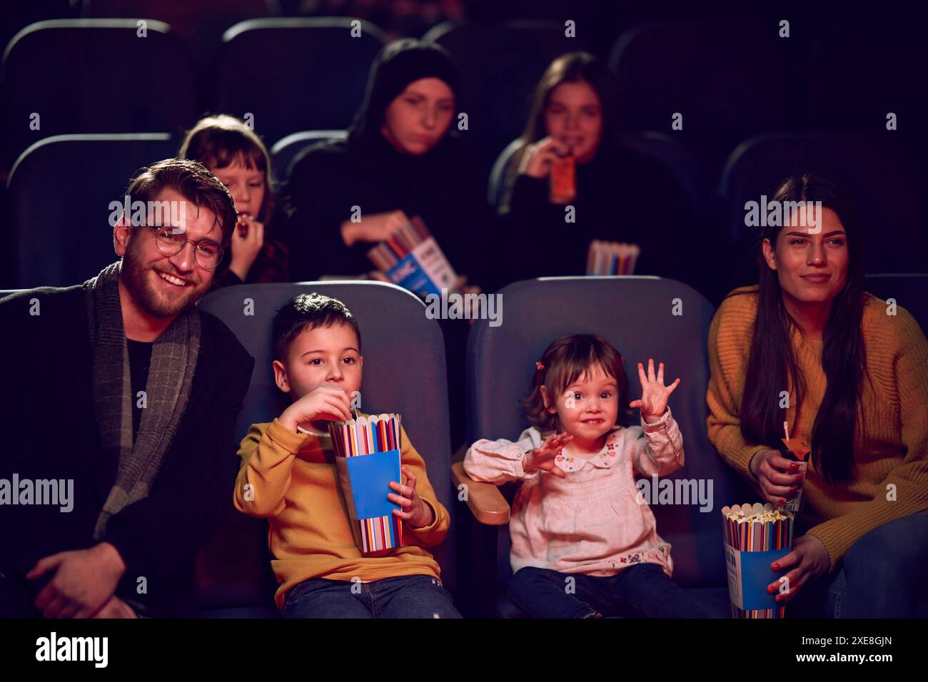 A modern family enjoys quality time together at the cinema, indulging ...