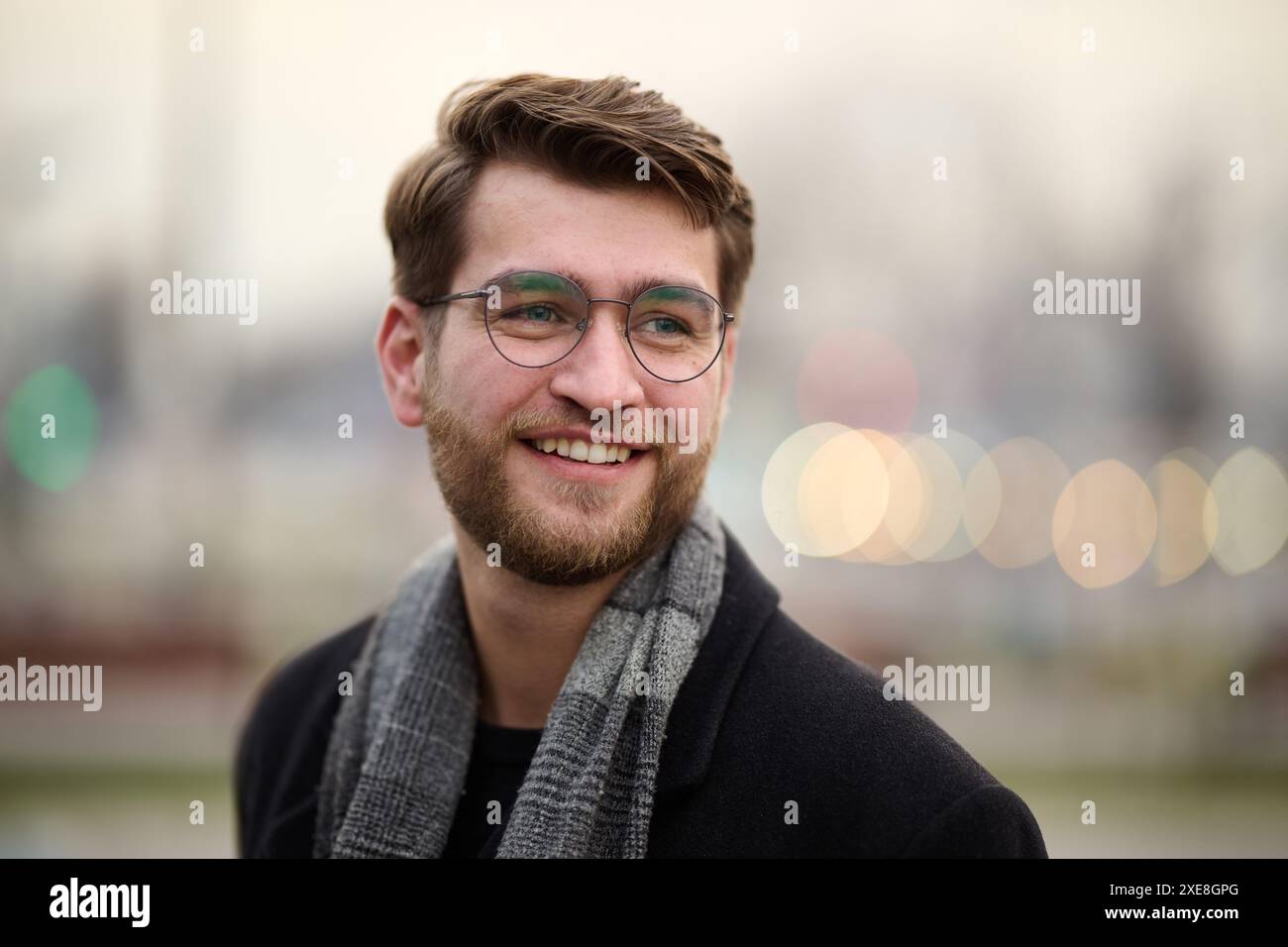 A handsome young man, dressed in a stylish suit, tie, and glasses ...