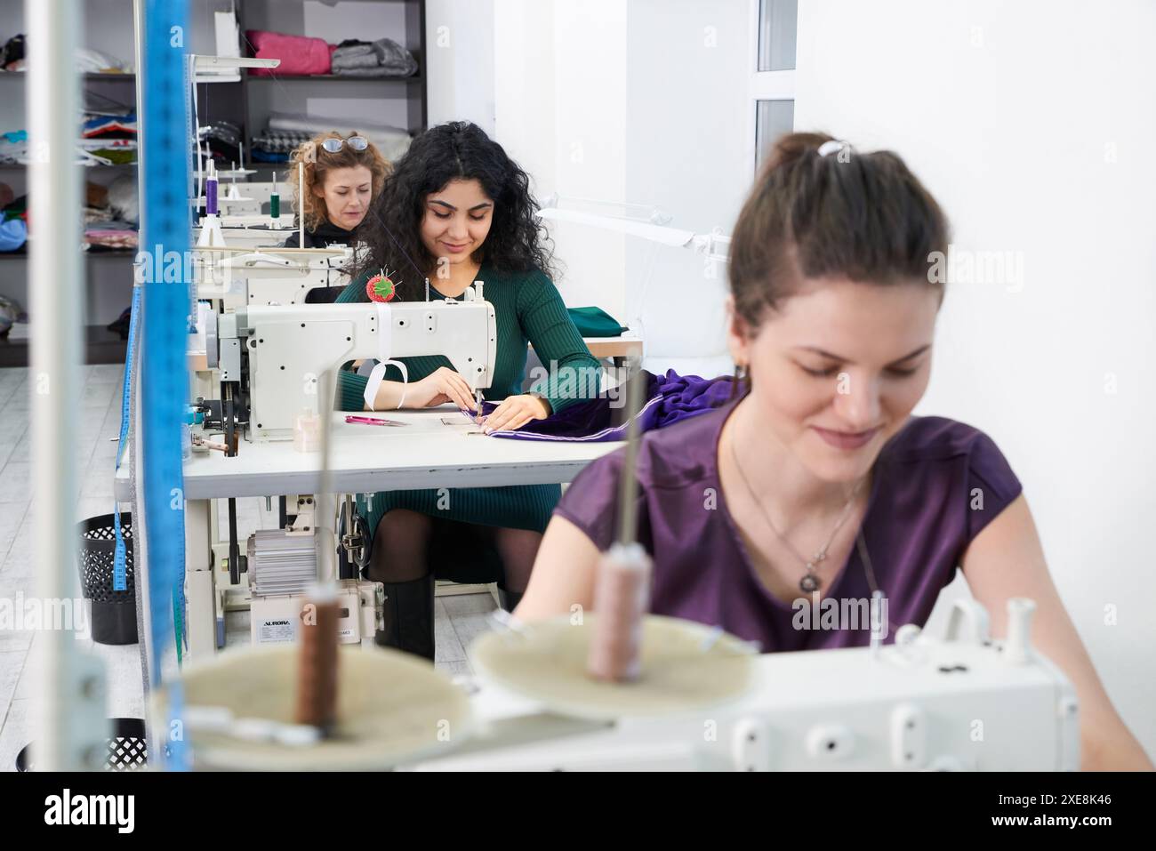 Young tailors sew clothes on sewing machine in atelier studio Stock ...