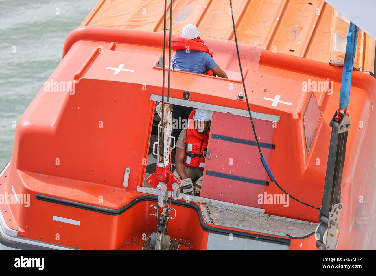 At sea. June 25, 2024: Crew members working on lifeboat maintenance ...