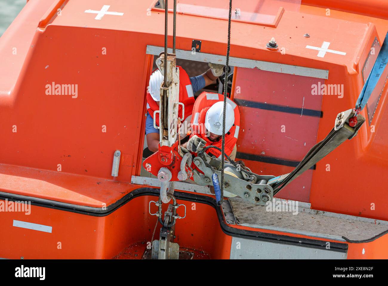 At sea. June 25, 2024: Crew members working on lifeboat maintenance ...