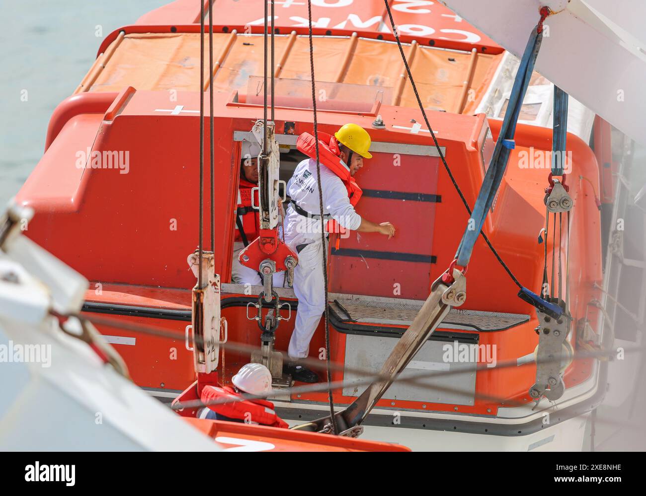 At sea. June 25, 2024: Crew members working on lifeboat maintenance ...