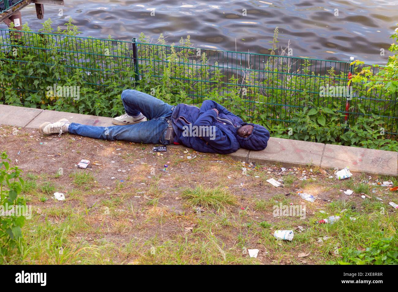 Berlin, Germany - May 21, 2024: A homeless man sleeps on the embankment ...