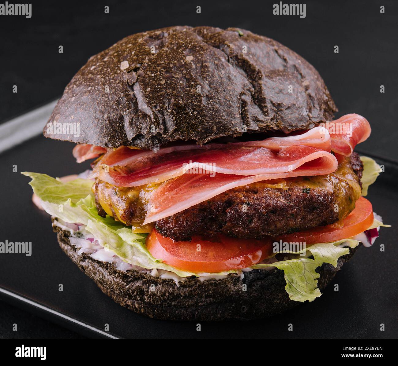 Modern black burger with prosciutto ham Stock Photo - Alamy